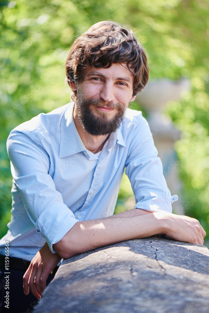 Portrait of a smiling man with a beard in a shirt resting on the ...