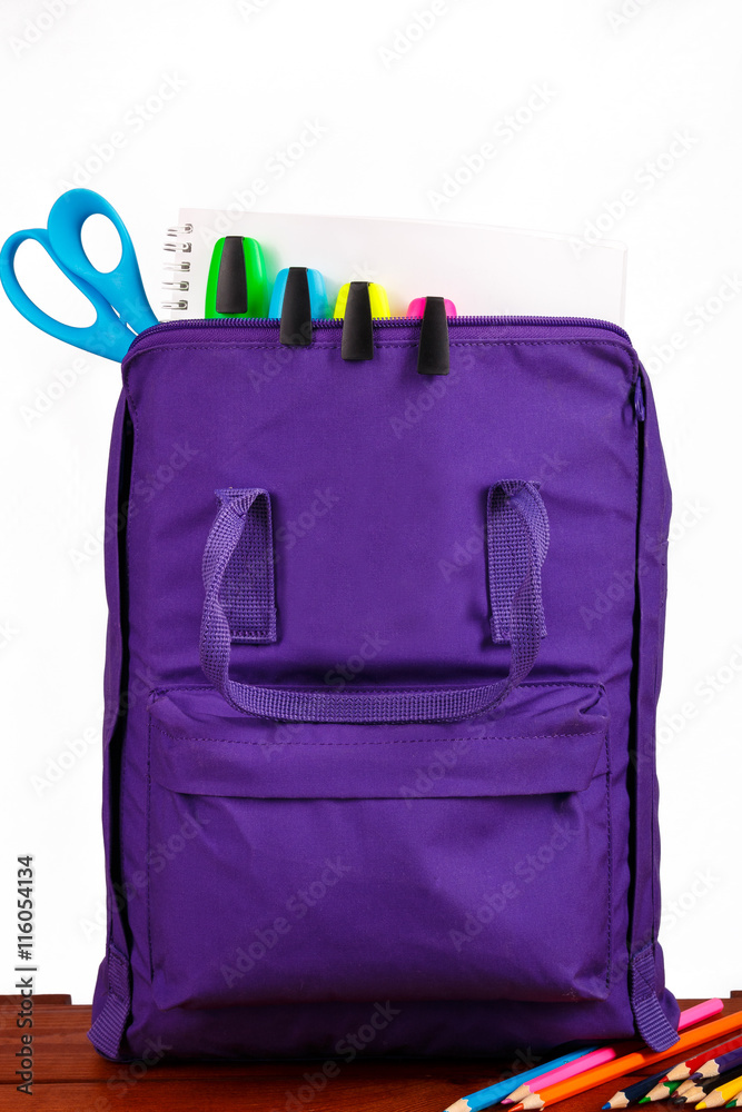 Open purple backpack with school supplies on wooden table. Back to ...