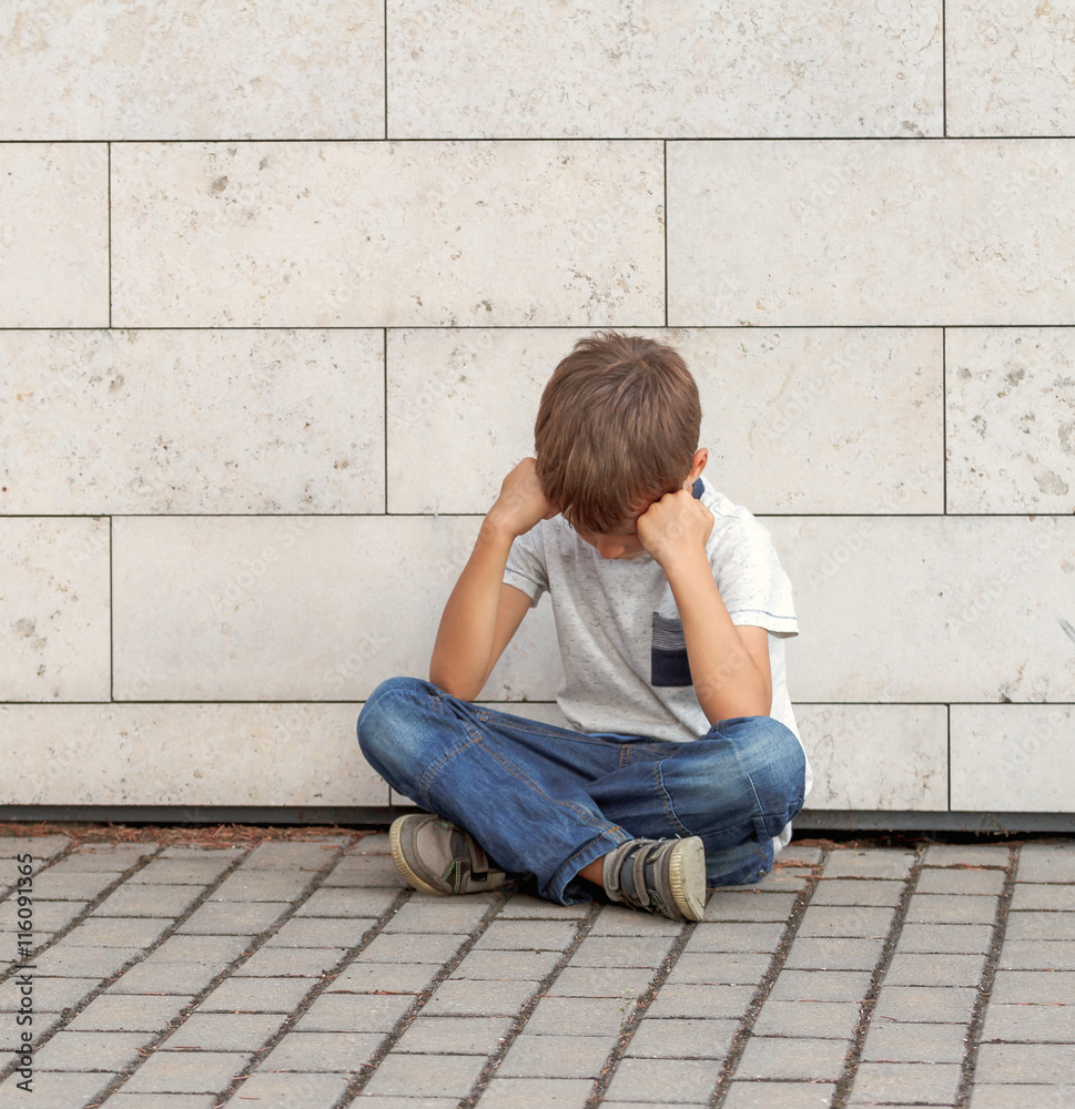 Sad, lonely, unhappy, disappointed child sitting alone on the ground ...