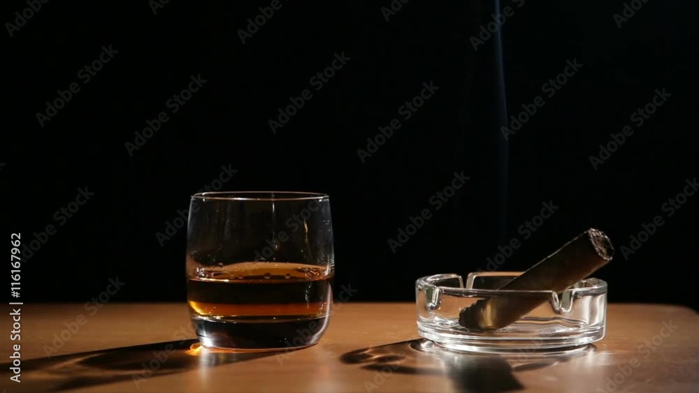 Glass of whiskey with smoking cigar.Glass of alcohol and smoking noble ...