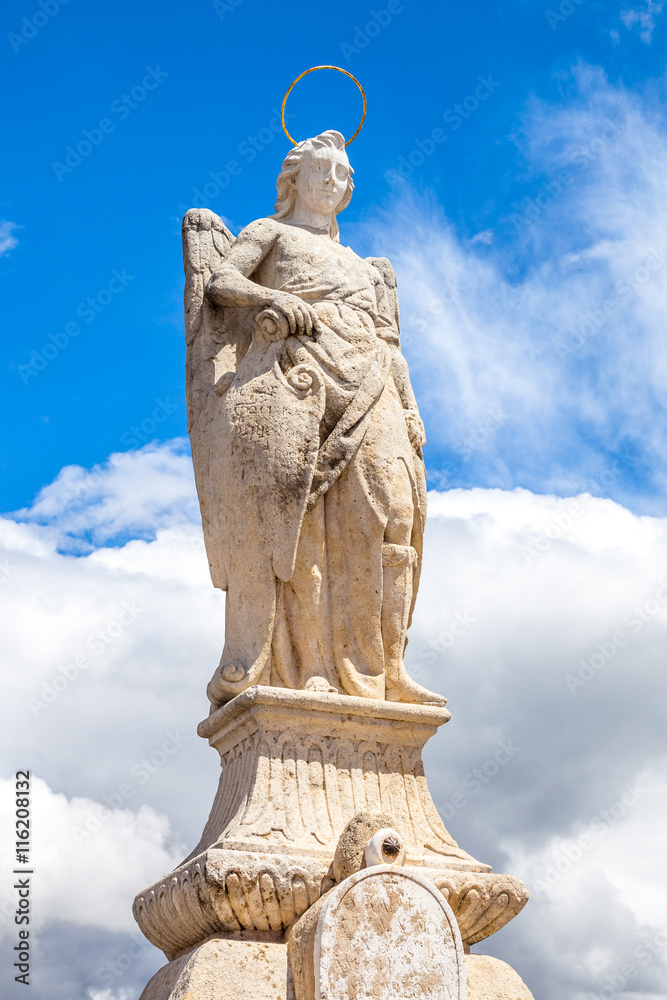 San Rafael Archangel statue in a sunny day and blue sky. The statue is ...