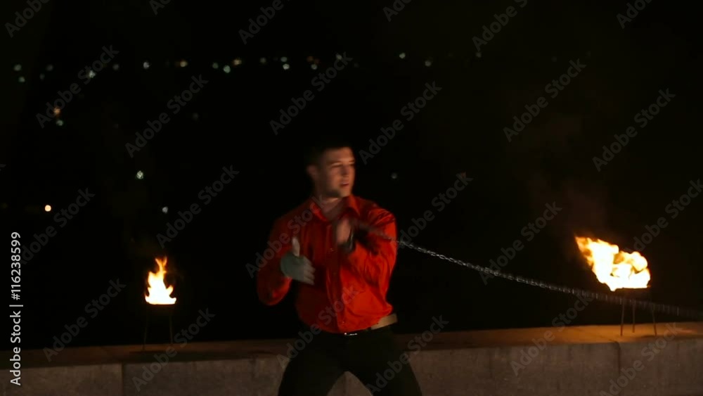 Artist man rotates the fireball.Man twist fiery circles on a fire show ...