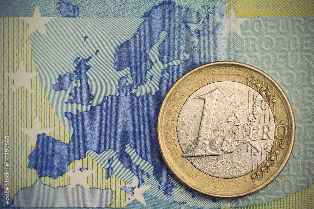 Detailed close up of an one euro coin on a blue twenty euro banknote ...