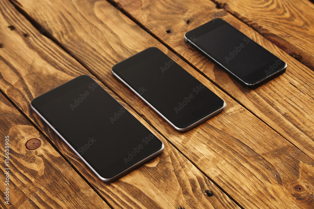 Side view on three various size smart touch devices on wooden aged ...