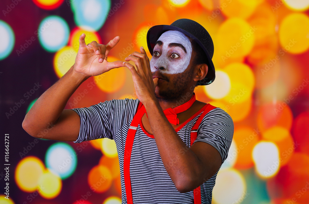 Pantomime man wearing facial paint posing for camera, using hands ...