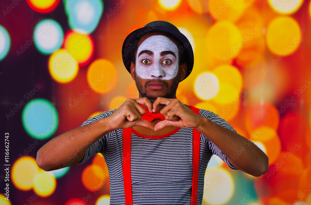 Pantomime man wearing facial paint posing for camera, using hands ...
