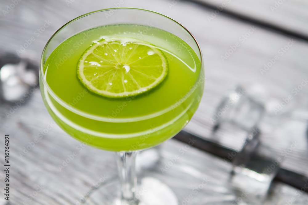Glass with green cocktail. Slice of lime. Daiquiri with sour juice ...
