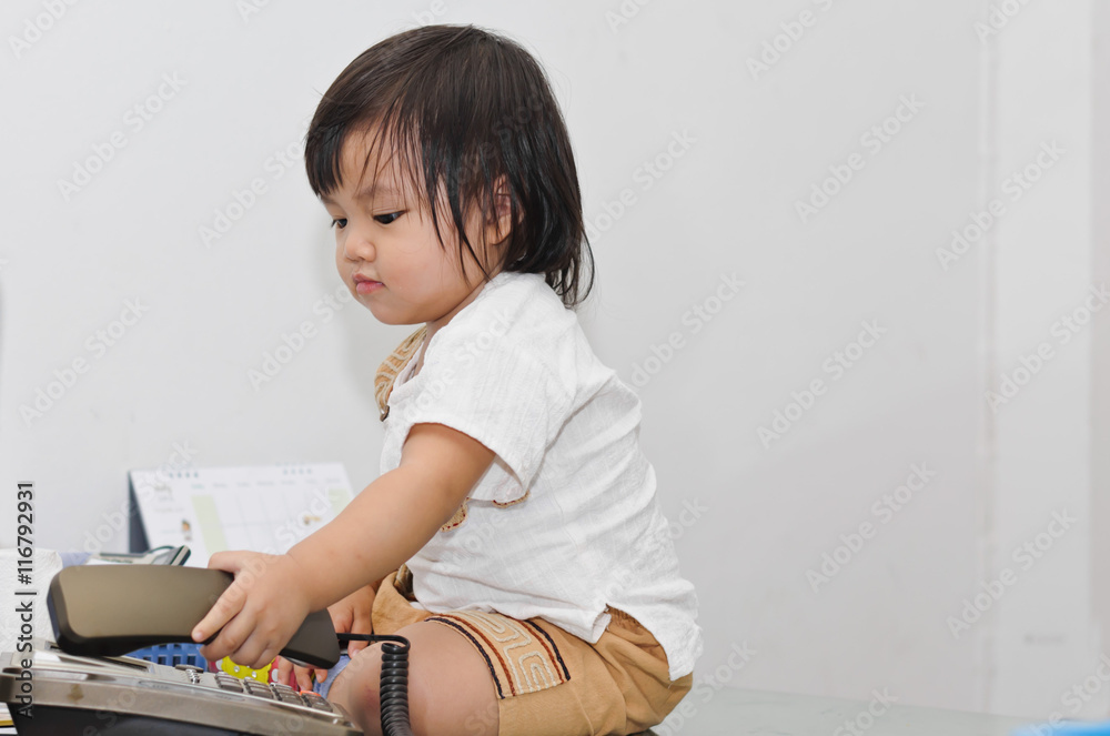 Asian girl baby seating on work desk and play telephone.(Soft focus ...