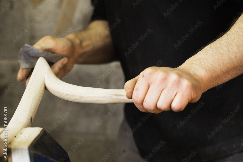 Close up of a man sanding a piece of curved wood in a carpentry ...