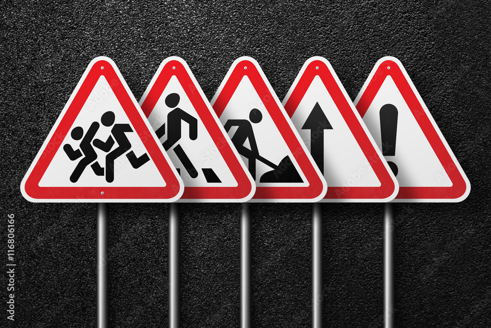 Road signs of the triangular shape are placed in a row on a background ...