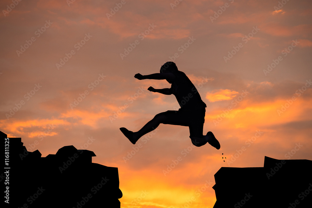 Silhouette of man jumping over cliff on sunset background , business ...