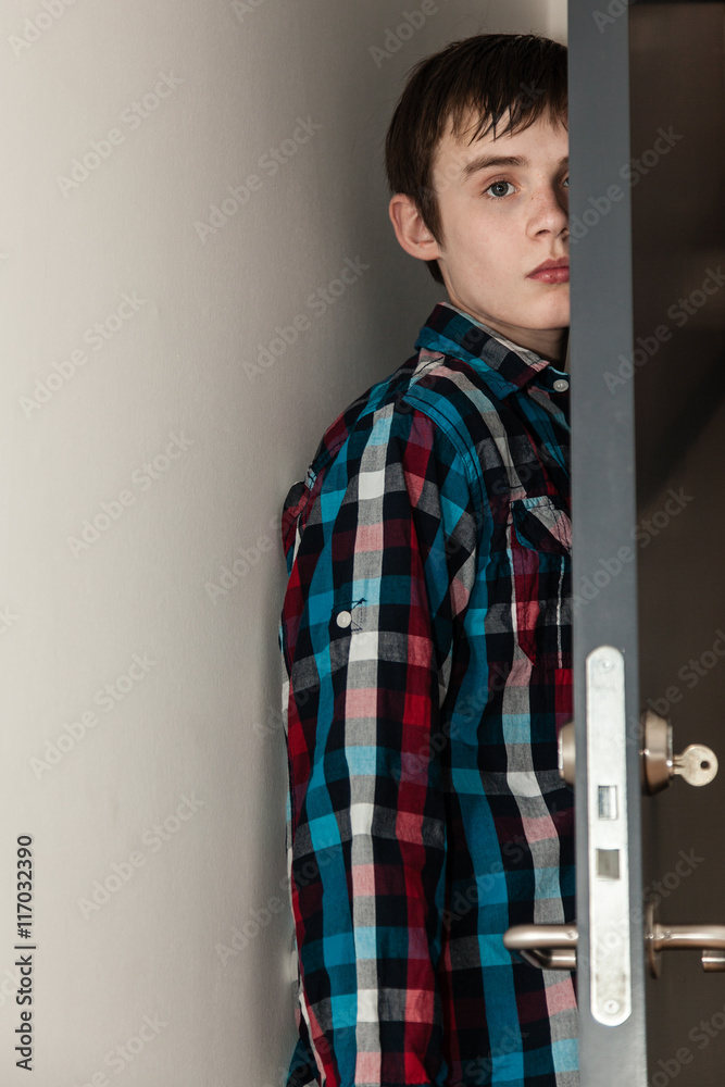 Teenage Boy Hiding Behind Open Door in Home Stock Photo | Adobe Stock