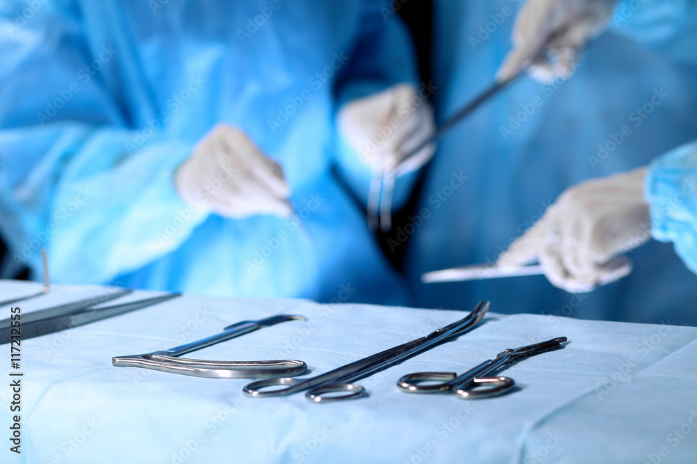 Surgical tools lying on the table while group of surgeons at background ...