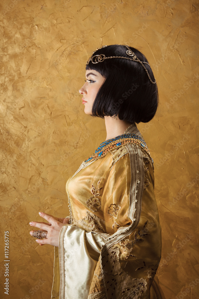 Beautiful woman like Egyptian Queen Cleopatra on golden background ...