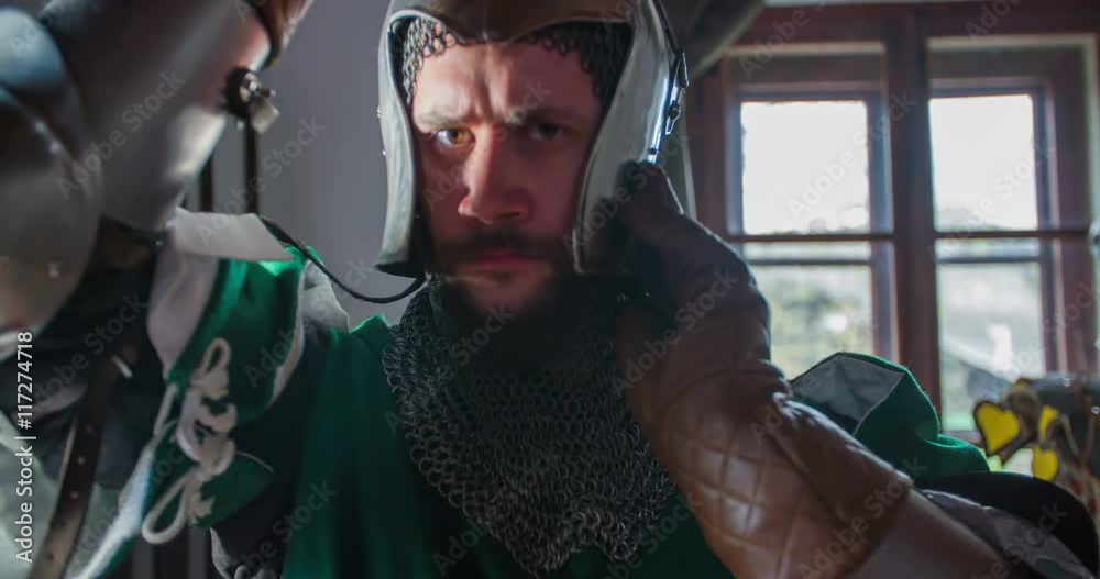 A sad knight is putting on a helmet and then he also closes it and ...