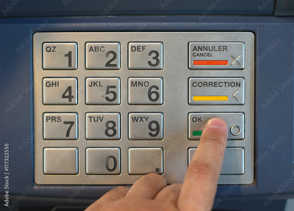 finger pressing buttons on cash machine to enter nip code on the keypad ...