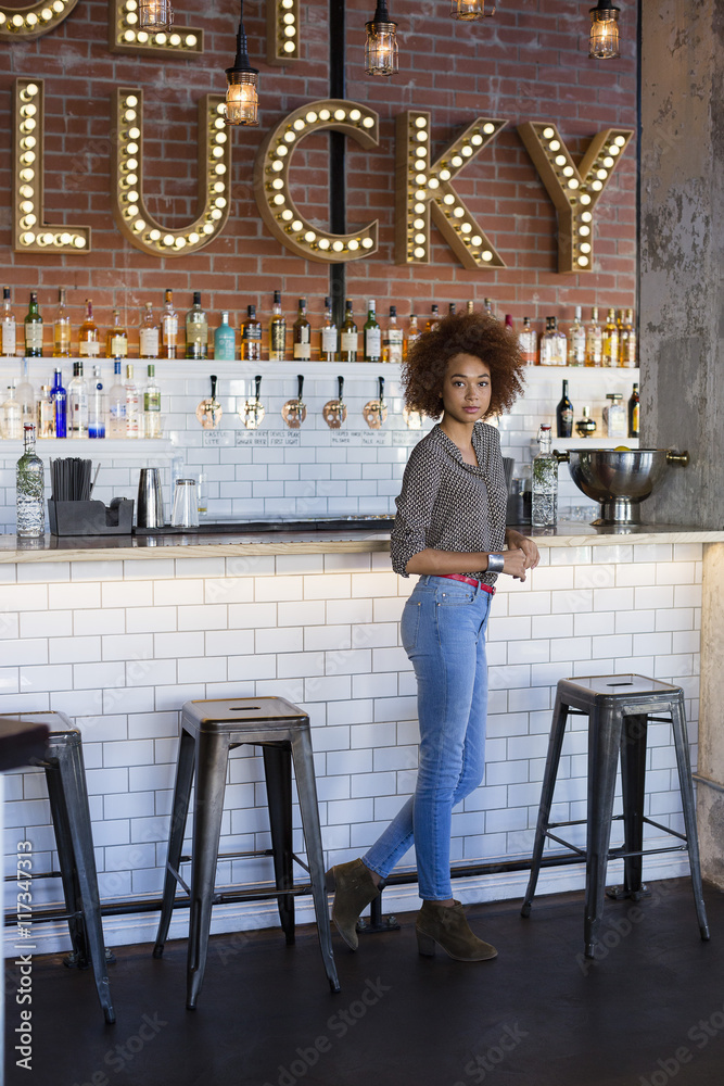 Portrait of a young woman standing at bar counter Stock Photo | Adobe Stock