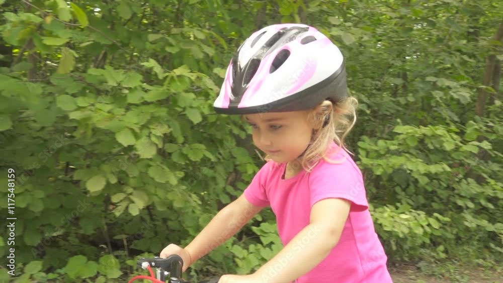 Happy child riding a bike in outdoor. Cute kid in safety helmet biking ...