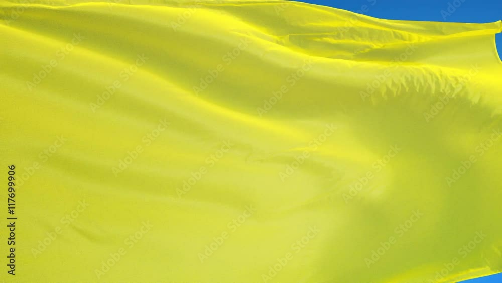 Bright yellow flag waving in slow motion against blue sky, seamlessly ...