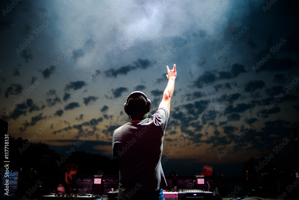 Club, disco DJ playing and mixing music for crowd of happy people ...