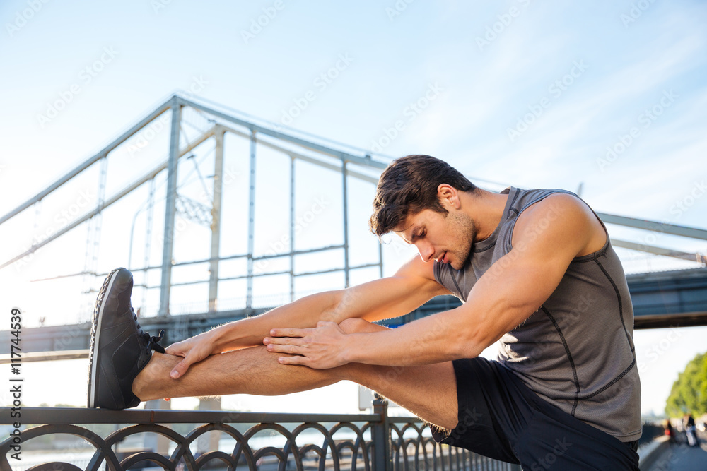 Foto Stock Sports man doing stretching leaning against the bridge ...