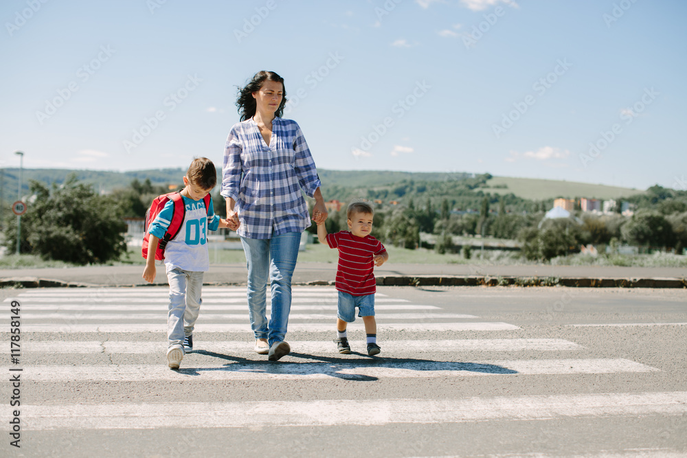 Road safety. Mother and her children crossing a street at a crosswalk ...
