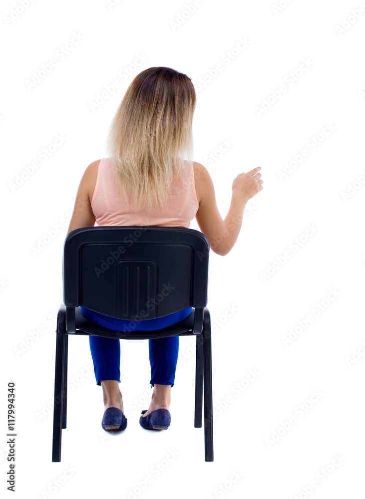 back view of young beautiful woman sitting on chair and pointing. girl ...