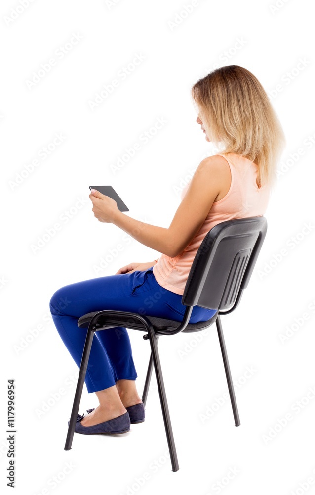 back view of woman sitting on chair and looks at the screen of the ...