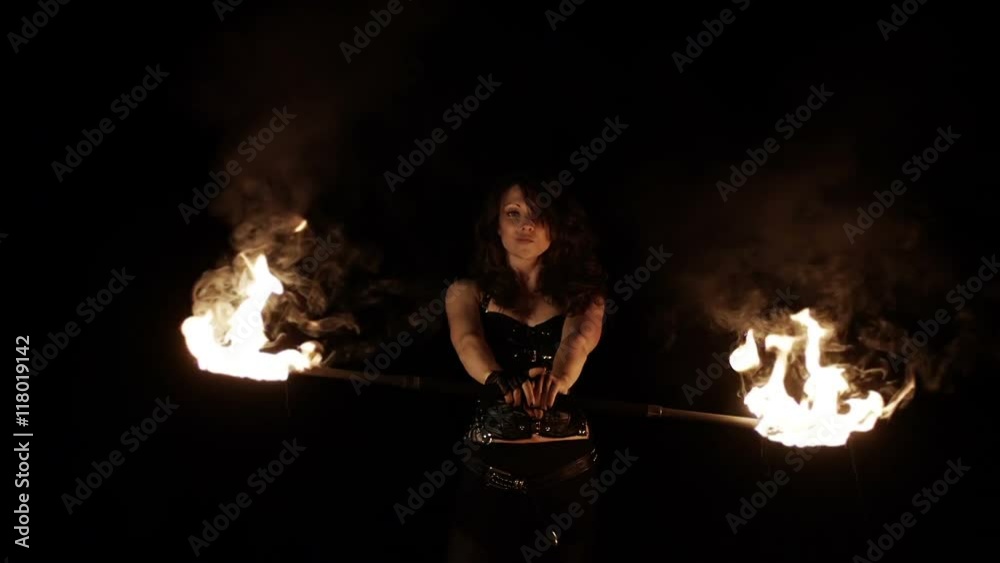 Female fire dance performer dancing with burning fire on black ...