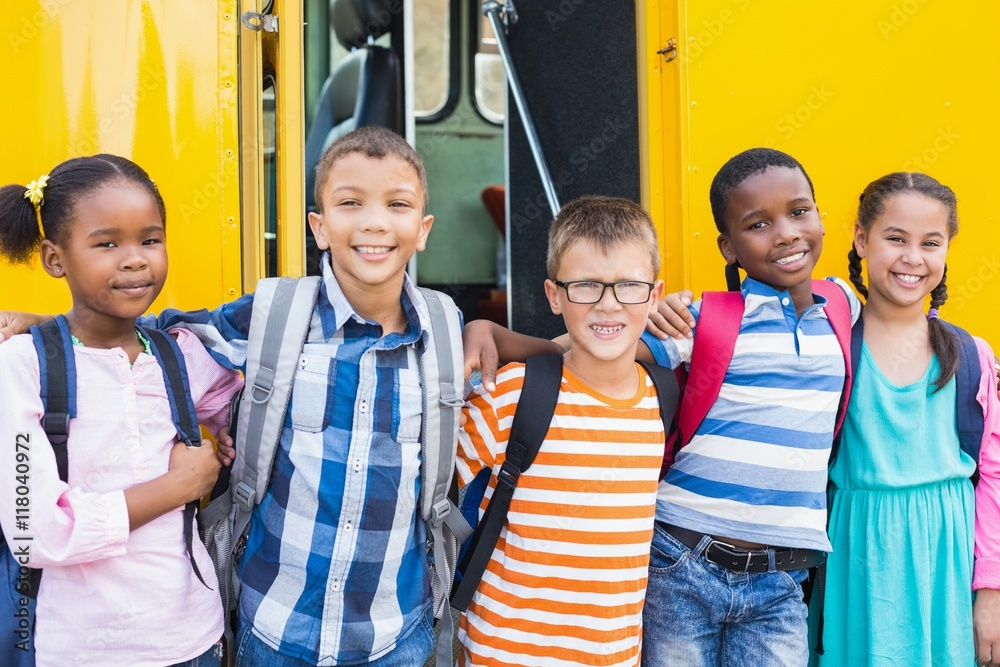 Smiling kids standing arm around in front of school bus Stock Photo ...