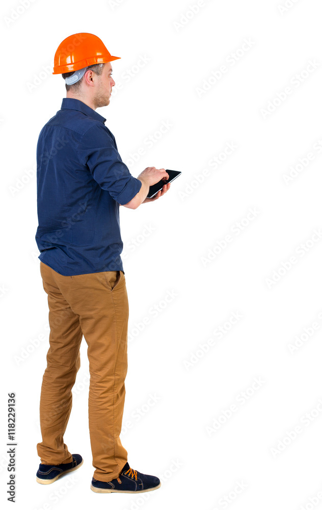 Backview of business man in construction helmet stands and enjoys ...
