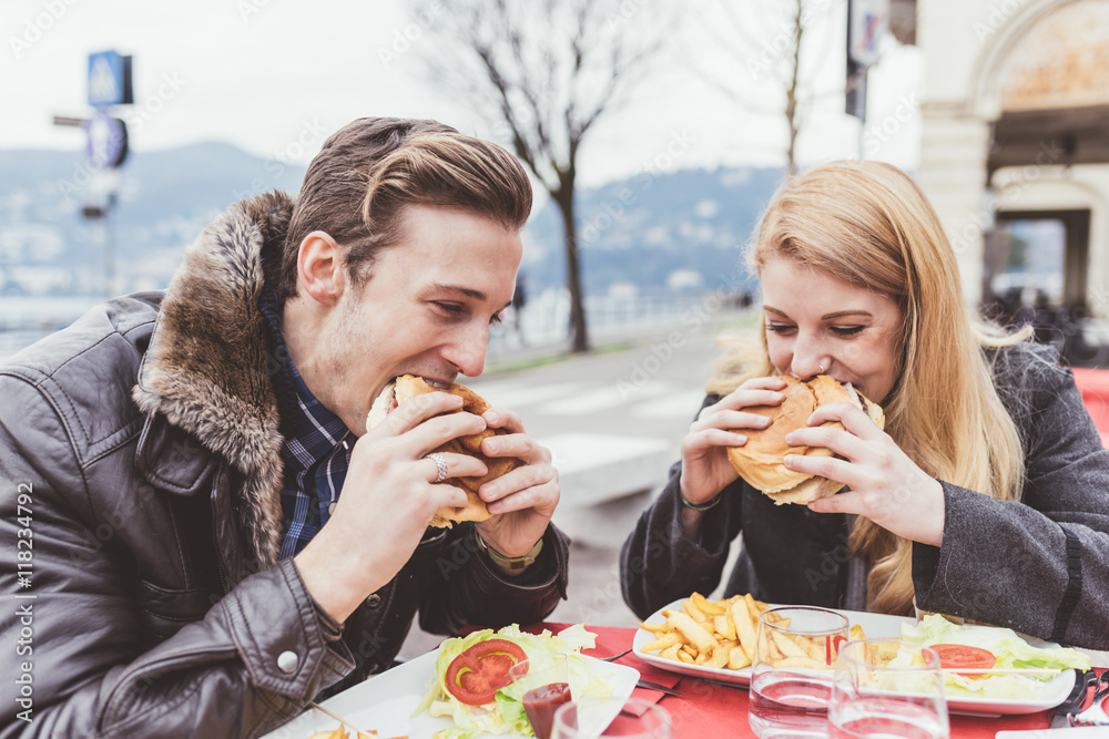Young couple eating burgers at sidewalk cafe, Lake Como, Italy Stock ...