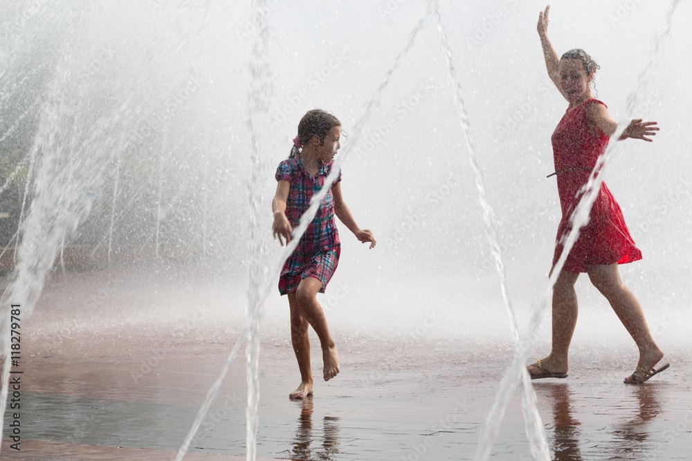 Young woman and little girl are dancing into the fountain. Stock Photo ...