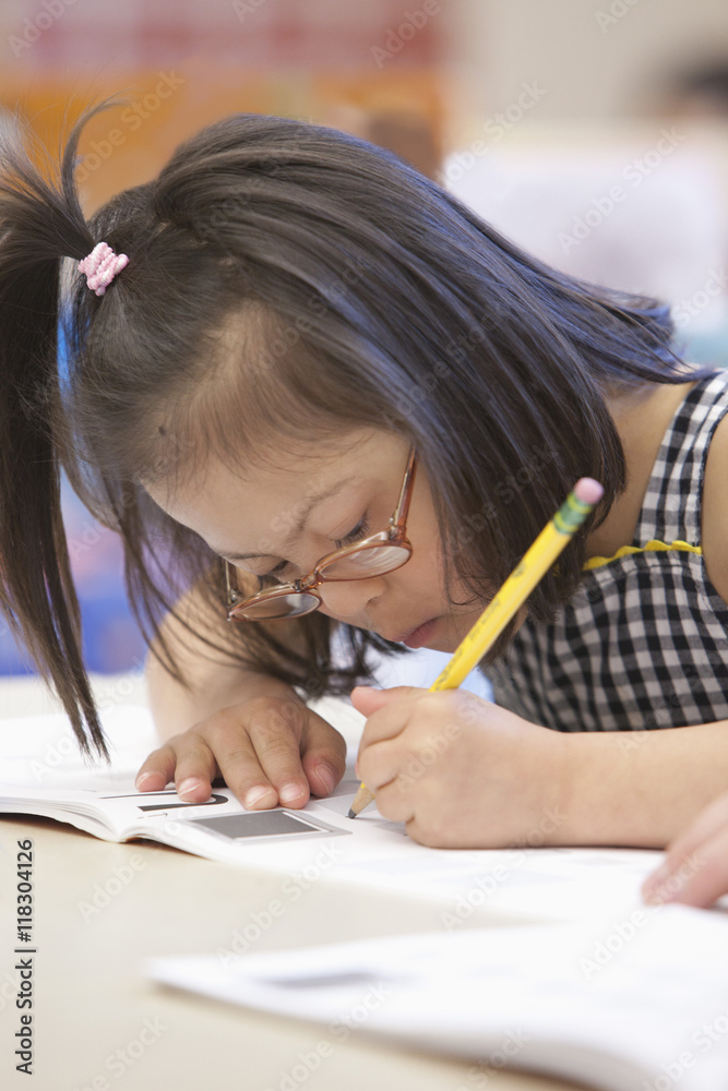 Mixed race Down syndrome student writing in workbook Stock Photo ...