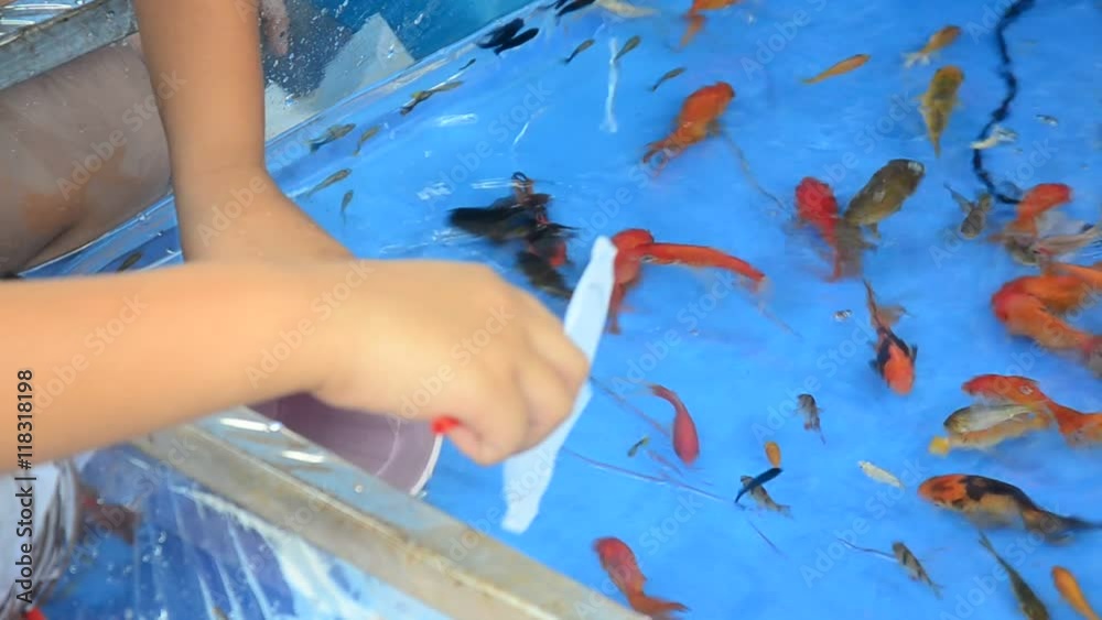 Thai children playing goldfish scooping game or paper scoop fish catch ...