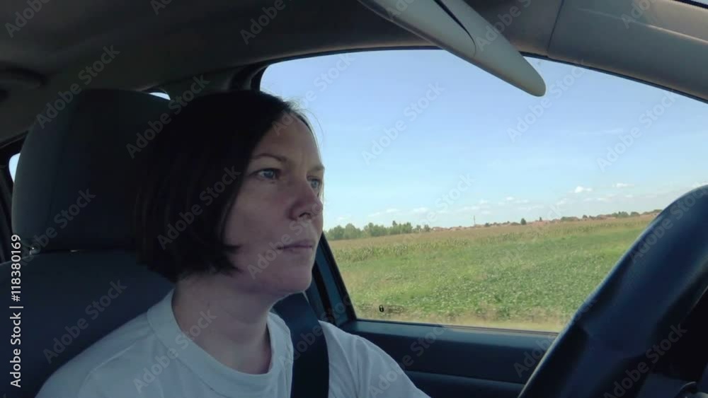 Woman driving car through plain landscape countryside on bright sunny ...