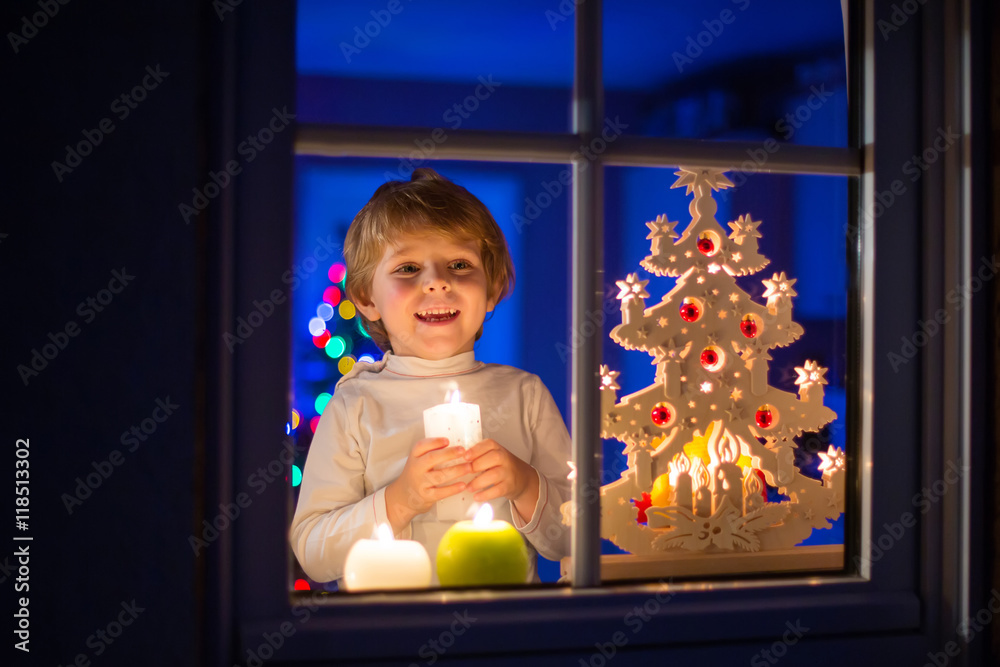 Little kid boy standing by window at Christmas time and holding Stock ...
