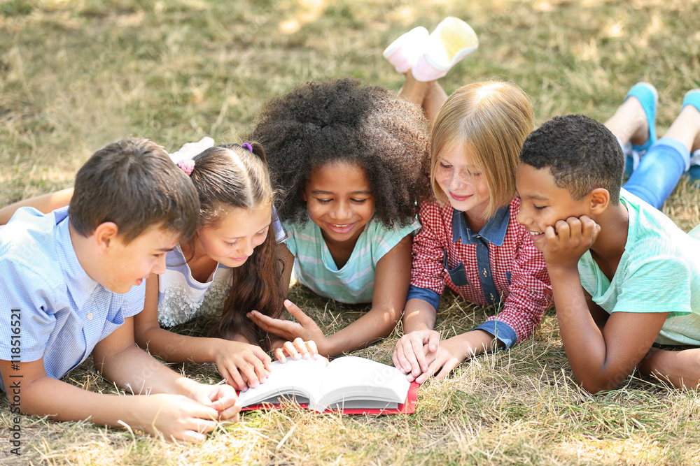 Cute kids reading book on green grass Stock Photo | Adobe Stock