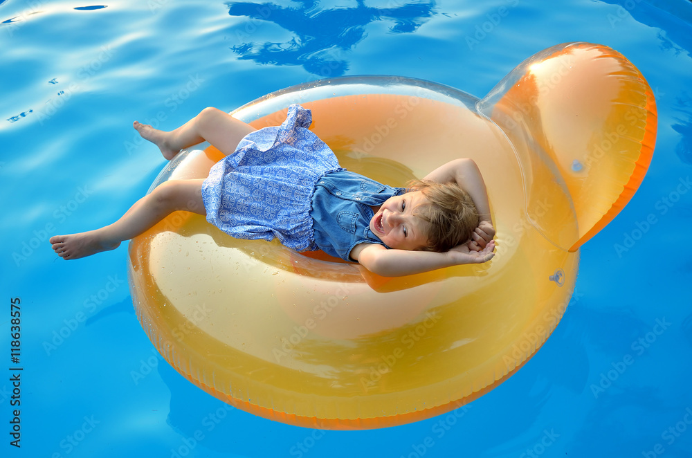 Little girl swimming in the pool on an inflatable chair, bright Stock ...