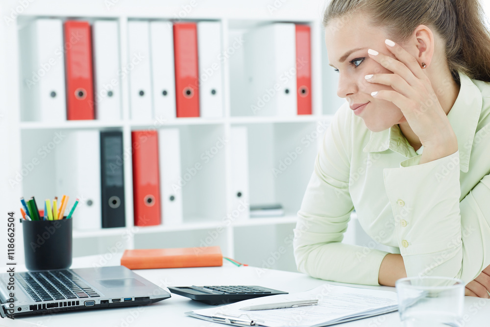 Bored secretary sitting at her desk and looking at the computer screen ...