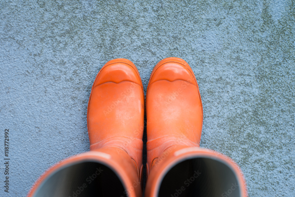 orange rubber boots on a concrete surface with copy space, top view ...