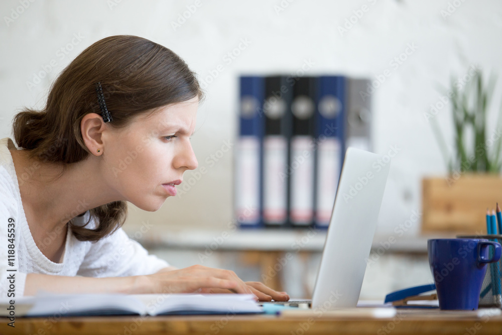 Young stressed businesswoman sitting with laptop and looking at screen ...