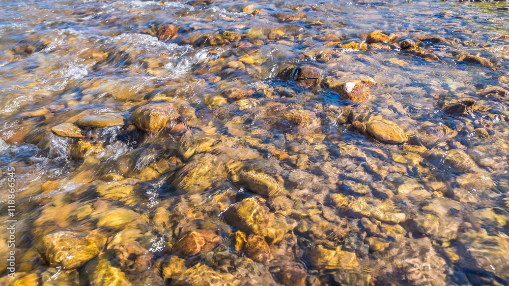 The bottom of the river close-up. The flow of water among the rocks ...