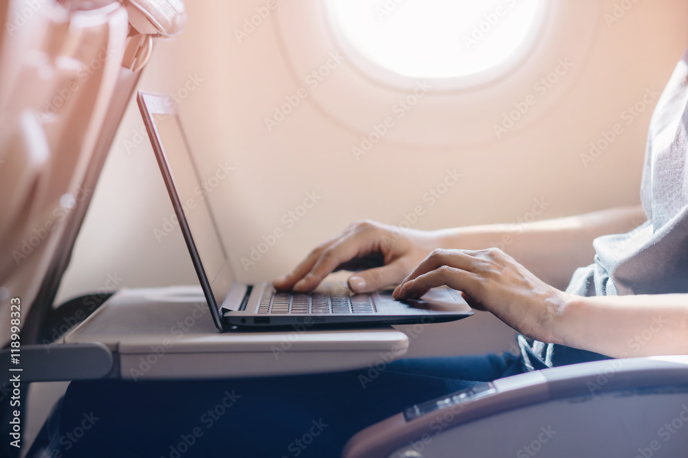 Woman typing text on laptop, young girl using modern laptop at airplane ...