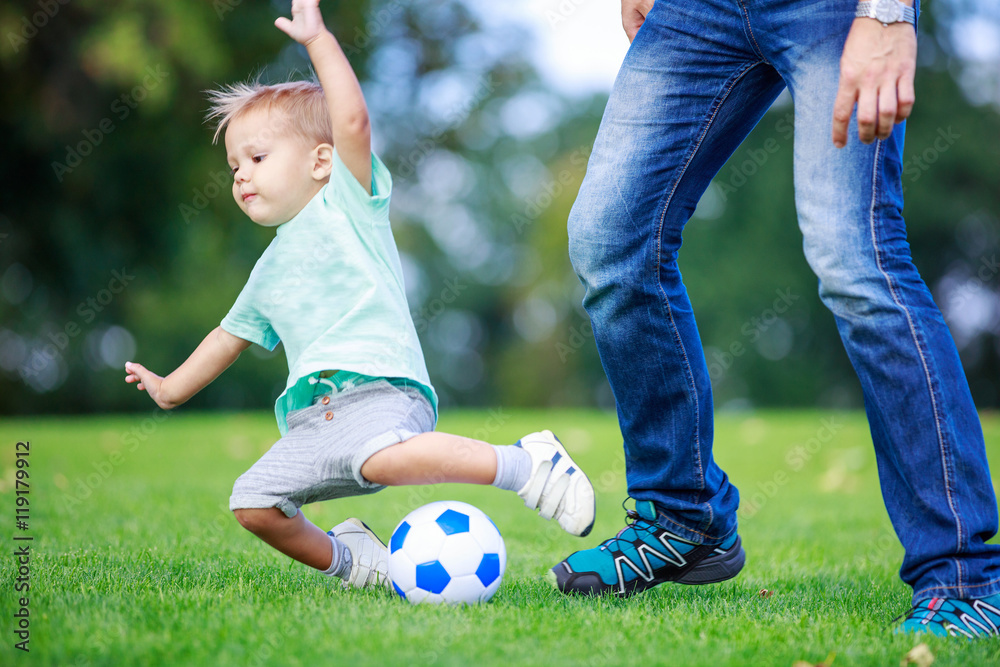 Little boy falling down while playing football with his father in park ...