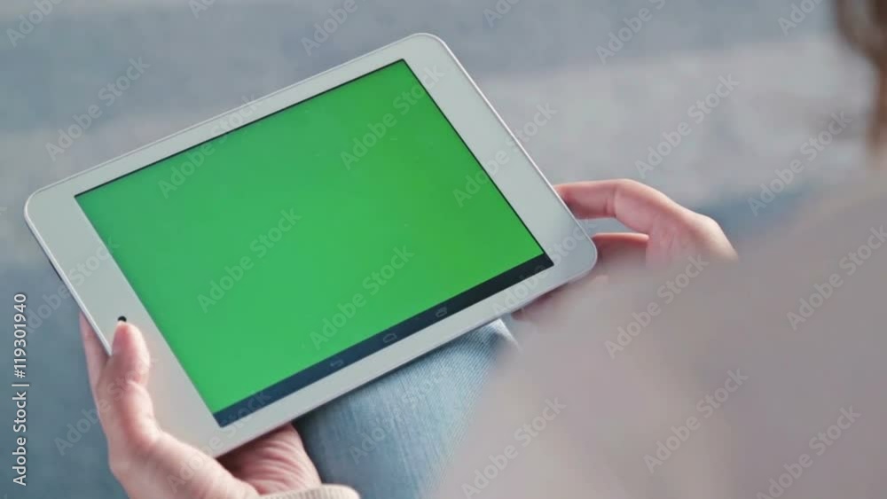 Woman looking at tablet with green screen. Close up shot of woman's ...