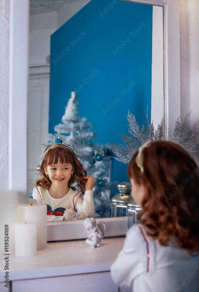 cute little girl looks in the mirror. The concept of the New Year and ...