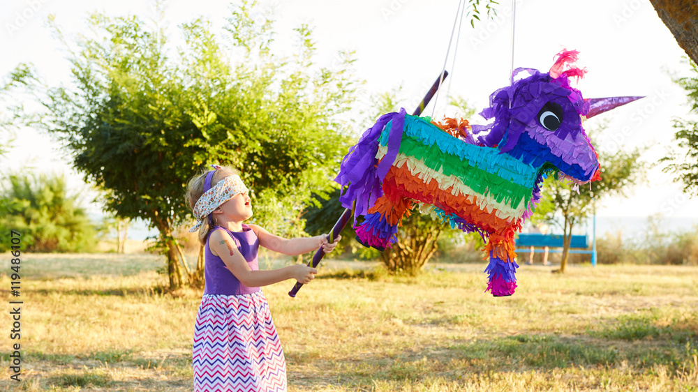 Young girl at an outdoor party hitting a pinata Stock Photo | Adobe Stock