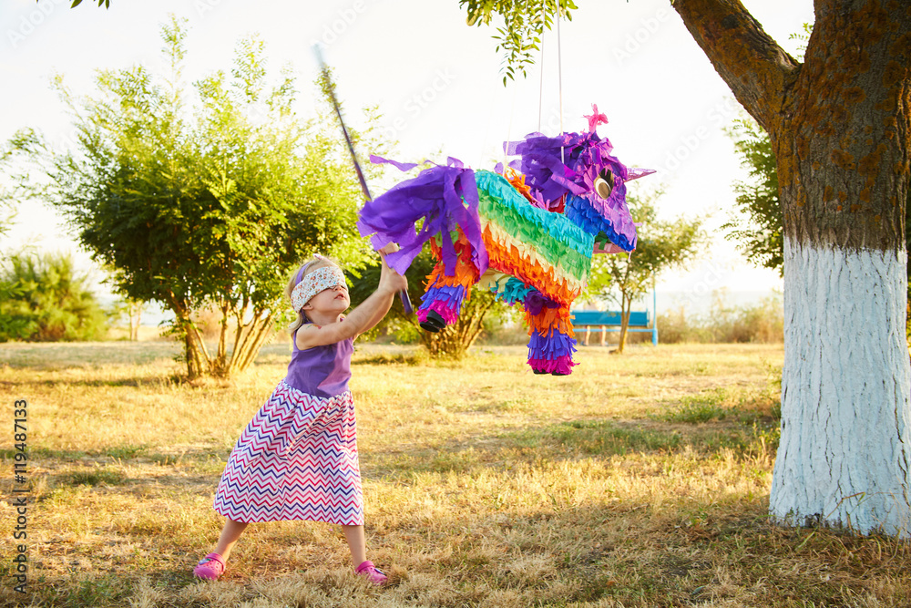 Young girl at an outdoor party hitting a pinata Stock Photo | Adobe Stock