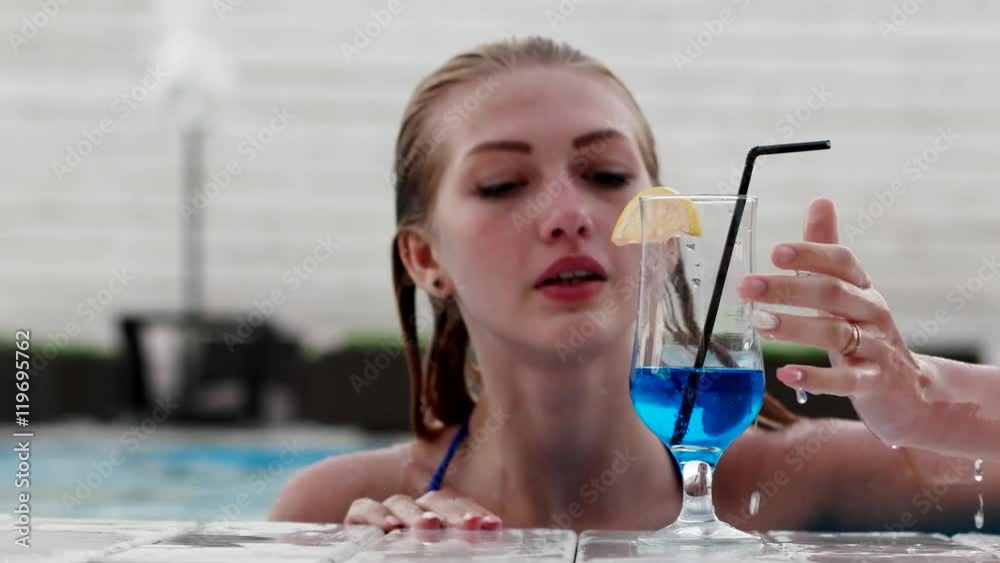 A girl swims to the blue alcoholic cocktail. young girl floating in the ...